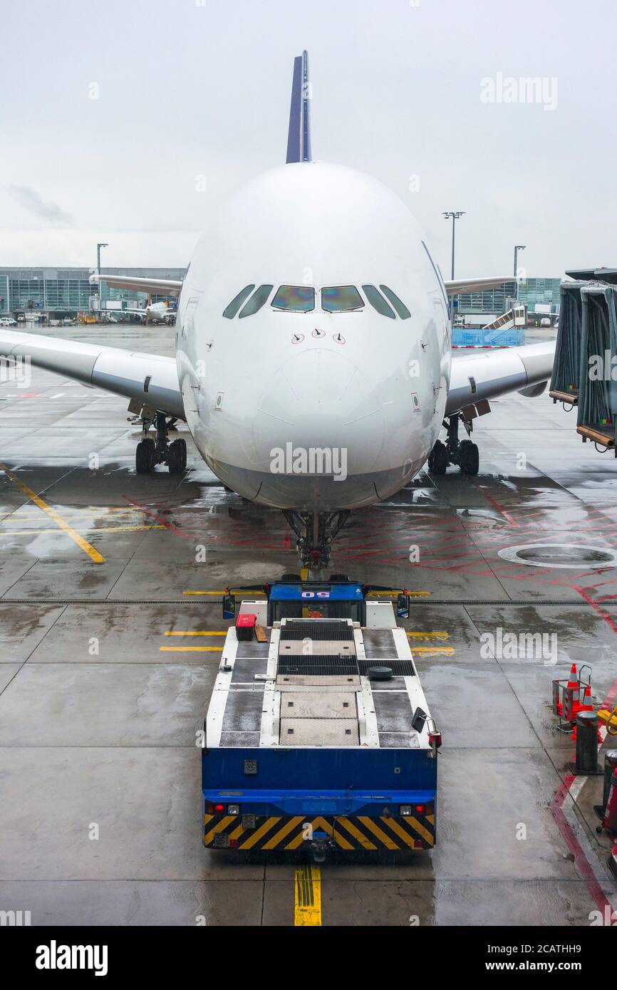 Pushback tug and a large airplane at an airport Stock Photo - Alamy