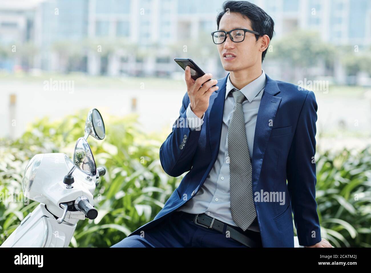 Confident young businessman in glasses recording voice message for his ...