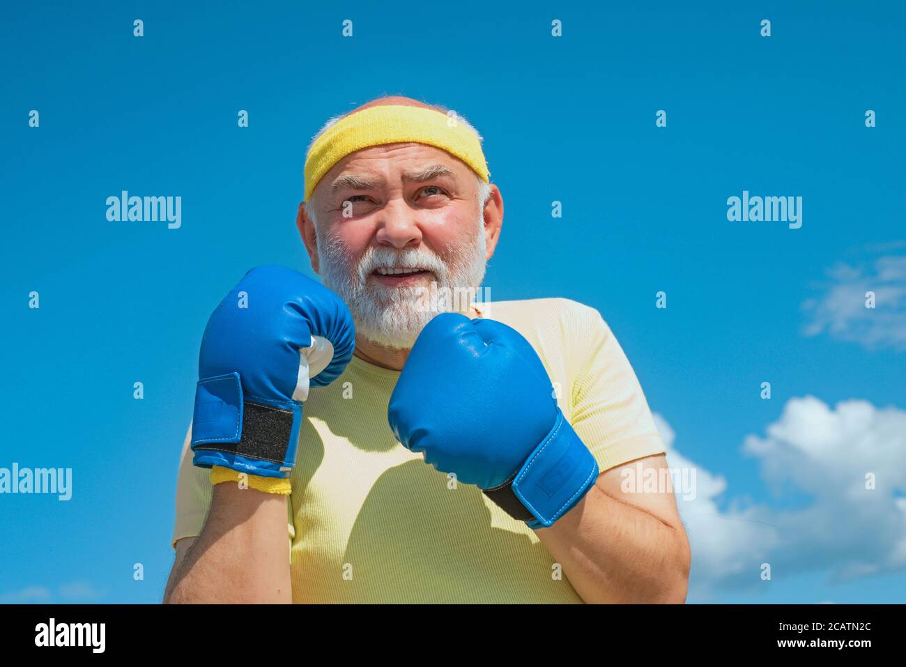Senior sportive man in boxing stance doing exercises with boxing gloves ...