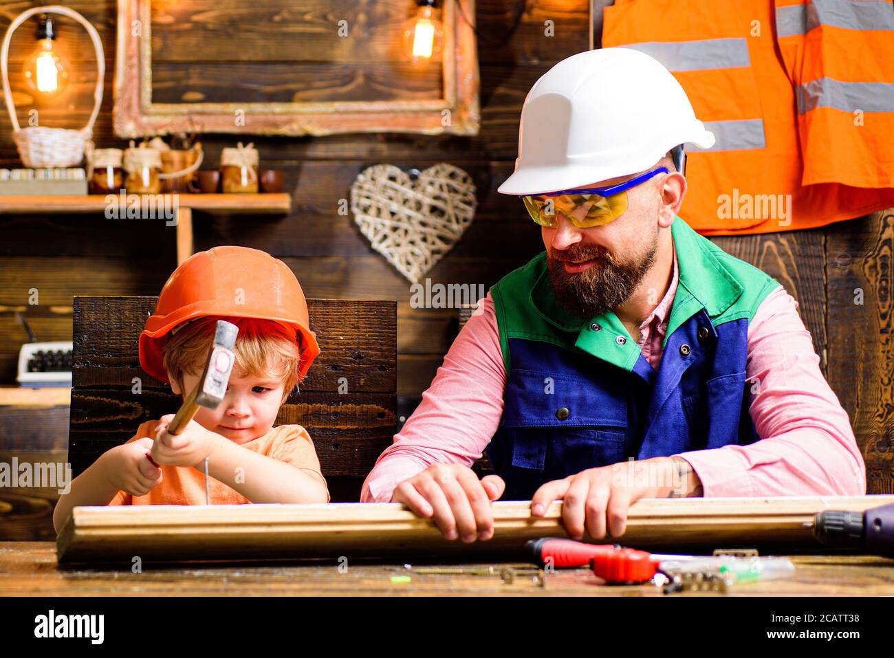 Father and son hammers nails with a hammer in a wooden board. Happy ...