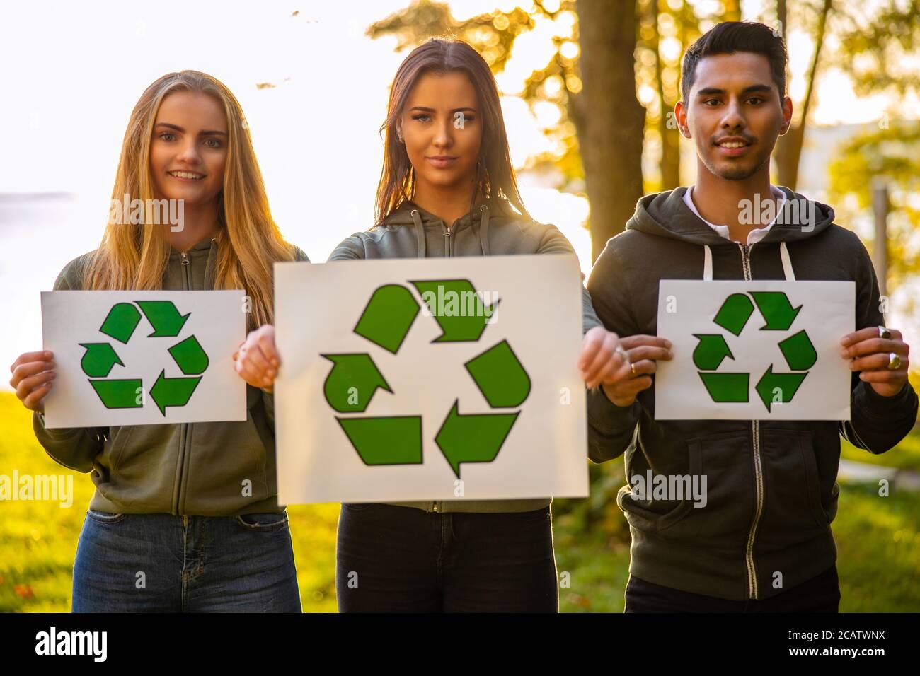 Young environment protective volunteers holding recycling symbol ...