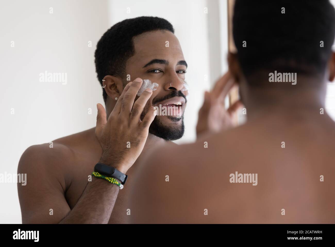 Close up positive African American young man applying face cream Stock ...