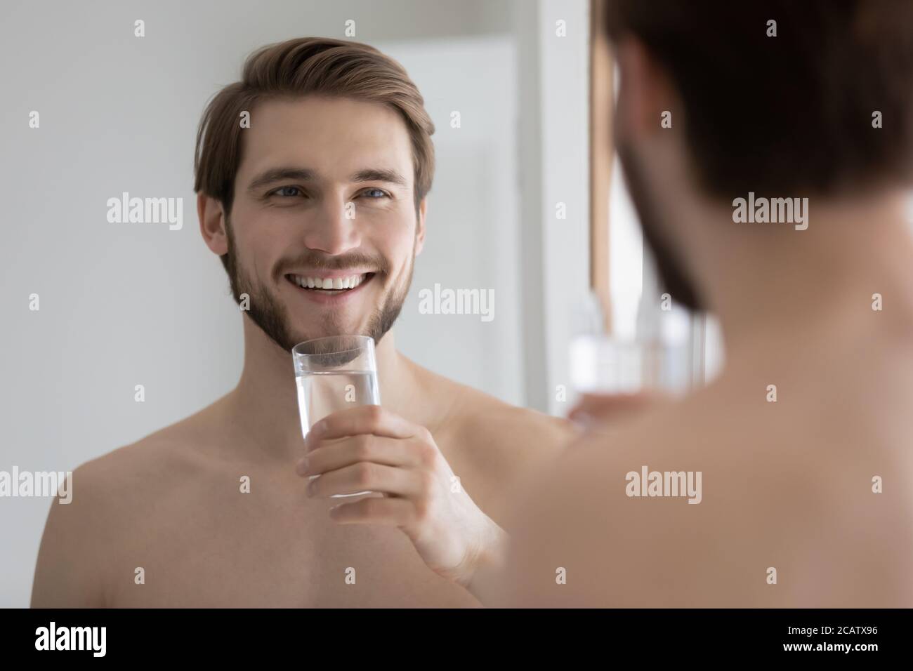Head shot mirror reflection smiling man holding glass of water Stock ...