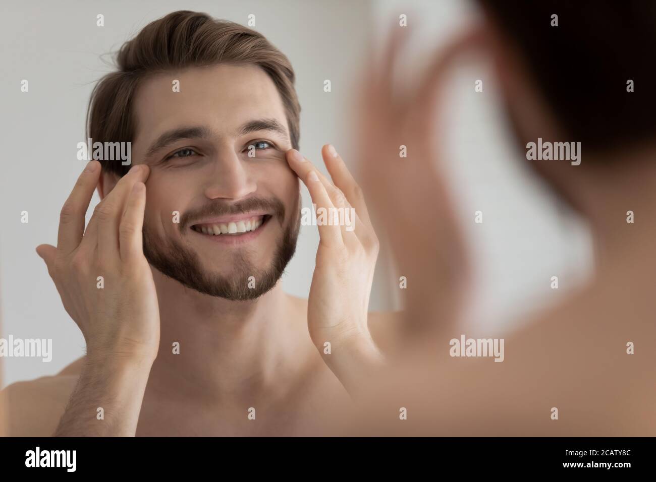 Close up mirror reflection smiling man touching skin under eyes Stock ...