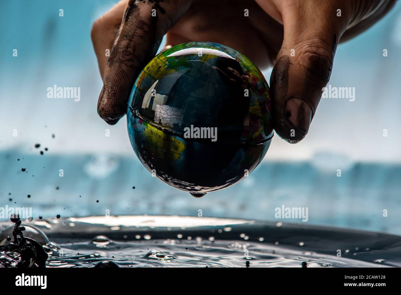 Soiled man's hand is pulling the Earth in the form of a globe out of ...