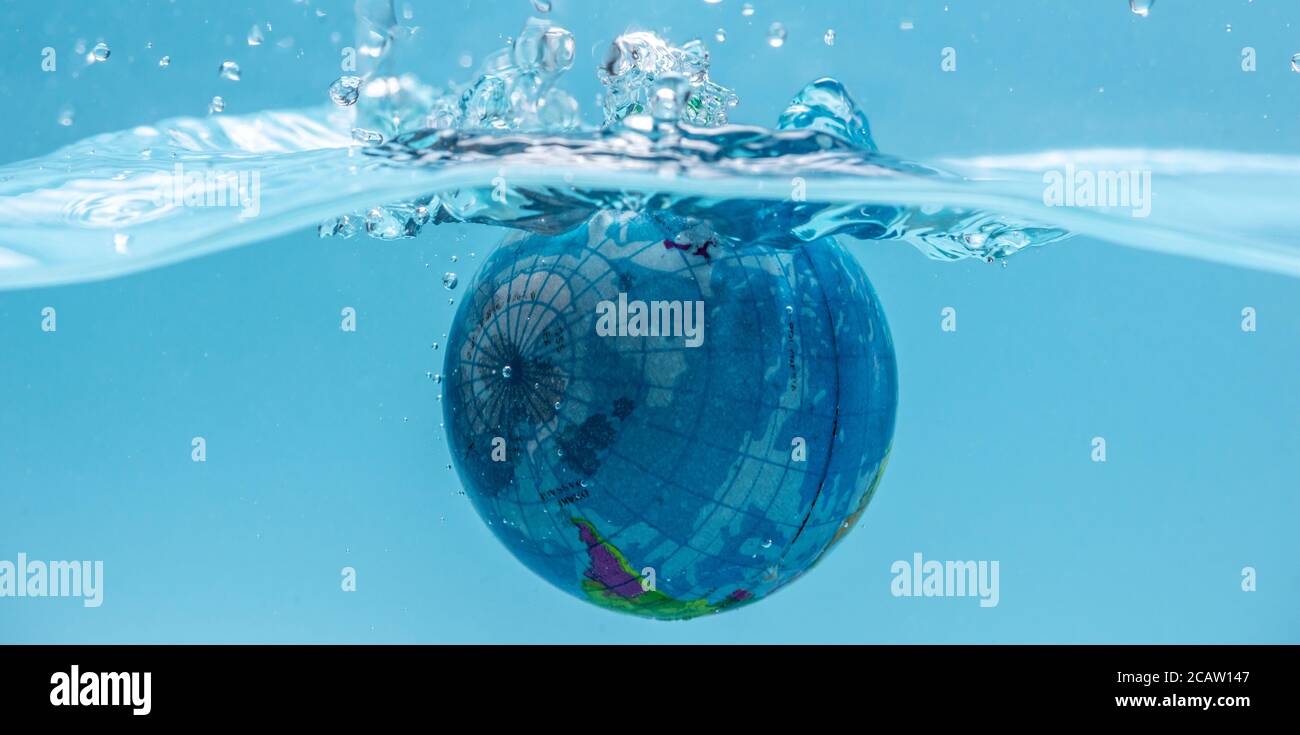 Planet Earth in the form of a globe is submerging in clear water ...