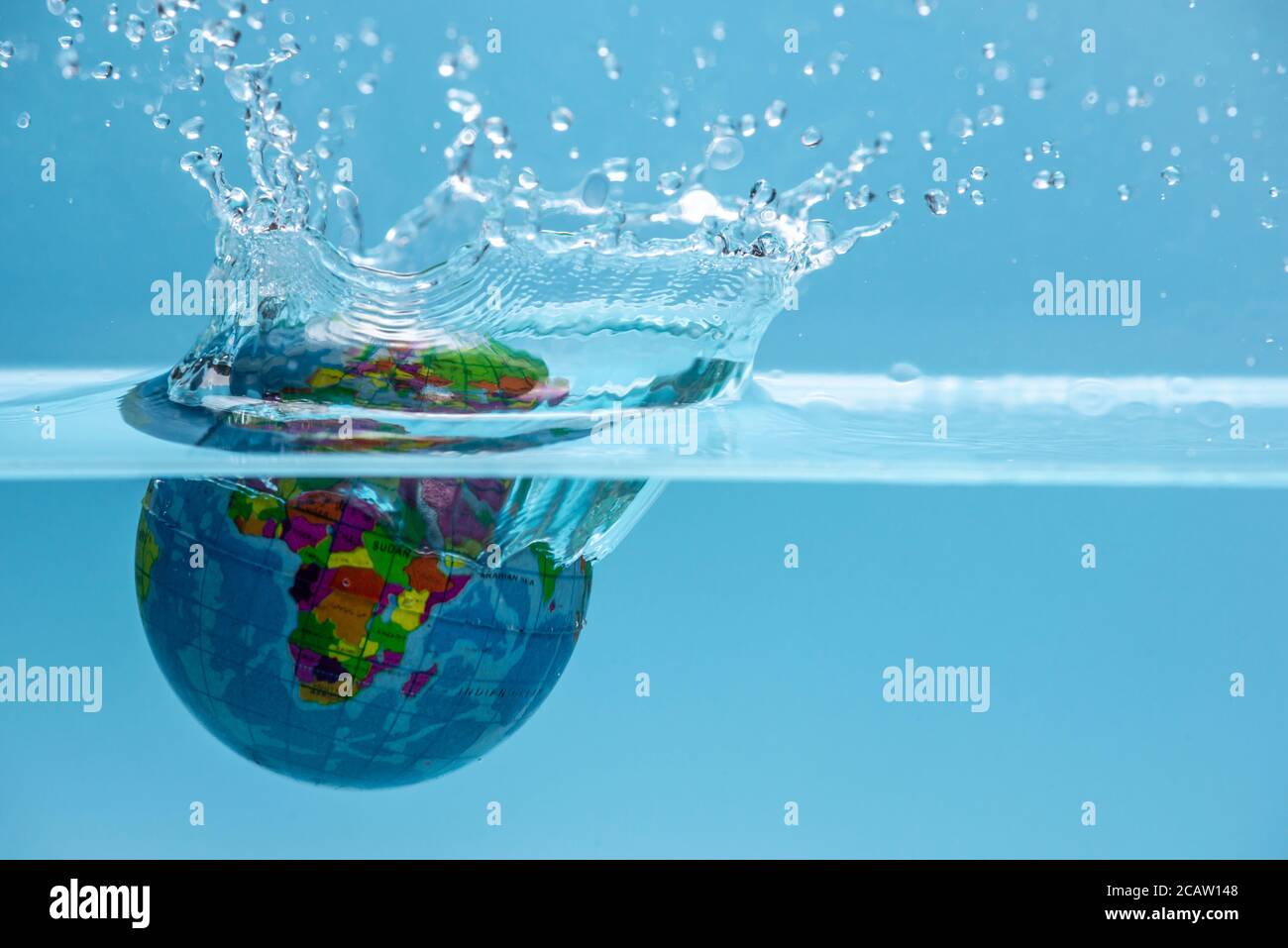 Planet Earth in the form of a globe is submerging in clear water ...