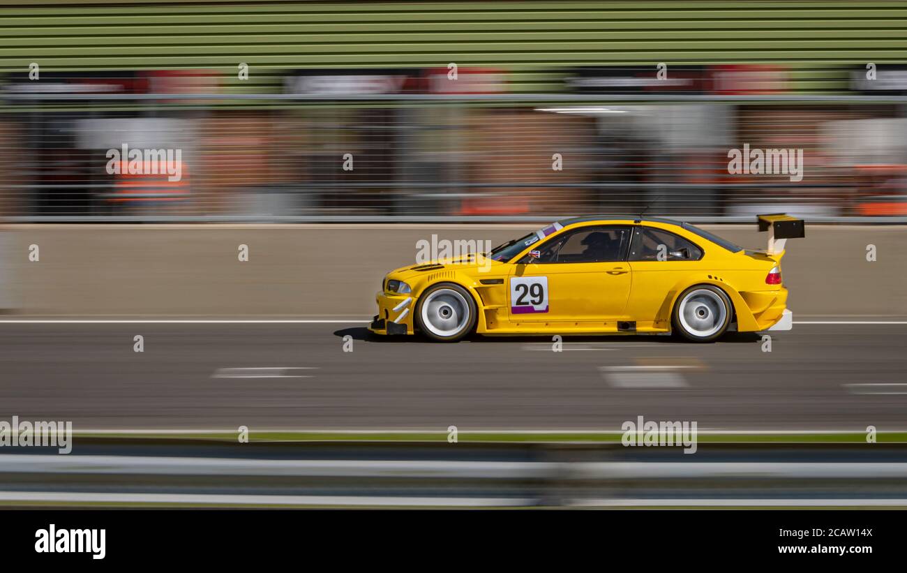 A panning shot of a yellow racing car as it circuits a track Stock ...