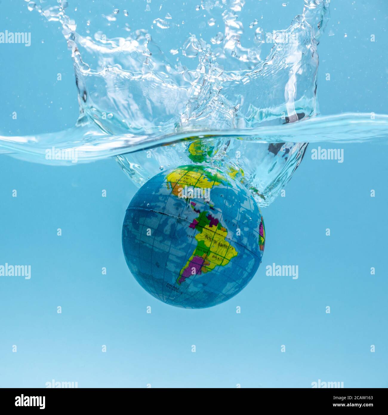 Planet Earth in the form of a globe is submerging in clear water ...