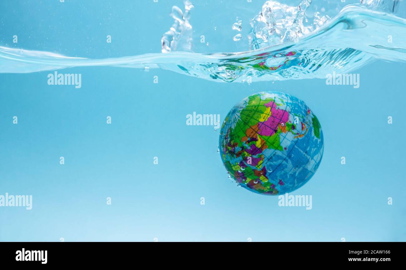 Planet Earth in the form of a globe is submerging in clear water ...