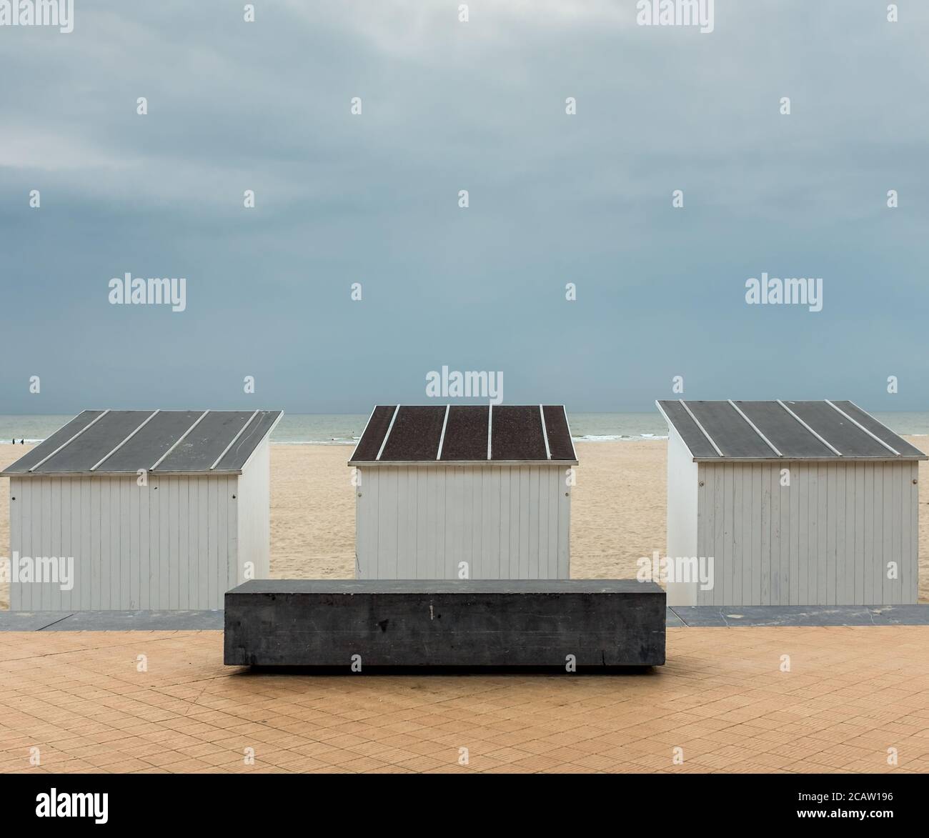 Three white beach huts against dark grey clouds Stock Photo - Alamy