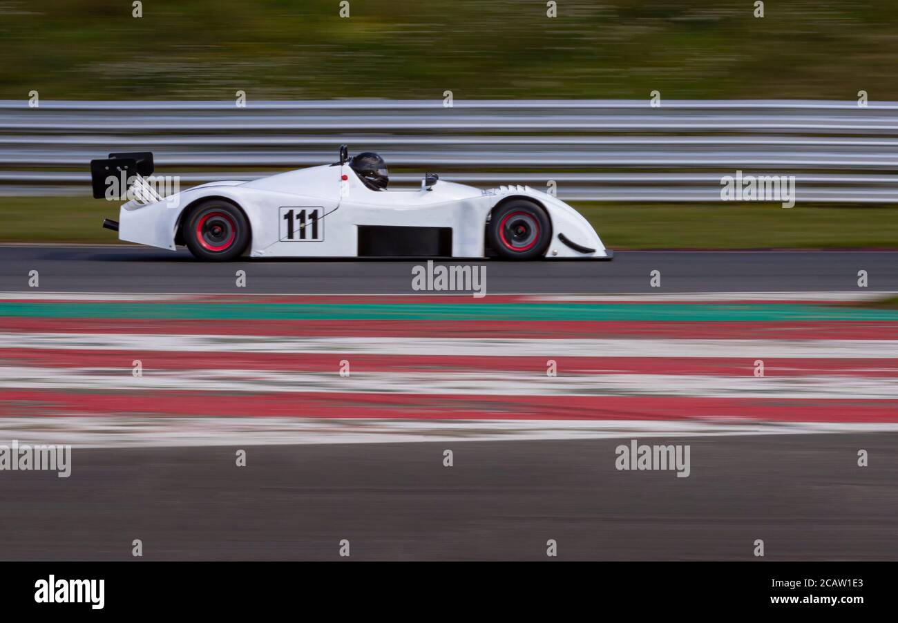 A panning shot of a white racing car as it circuits a track Stock Photo ...