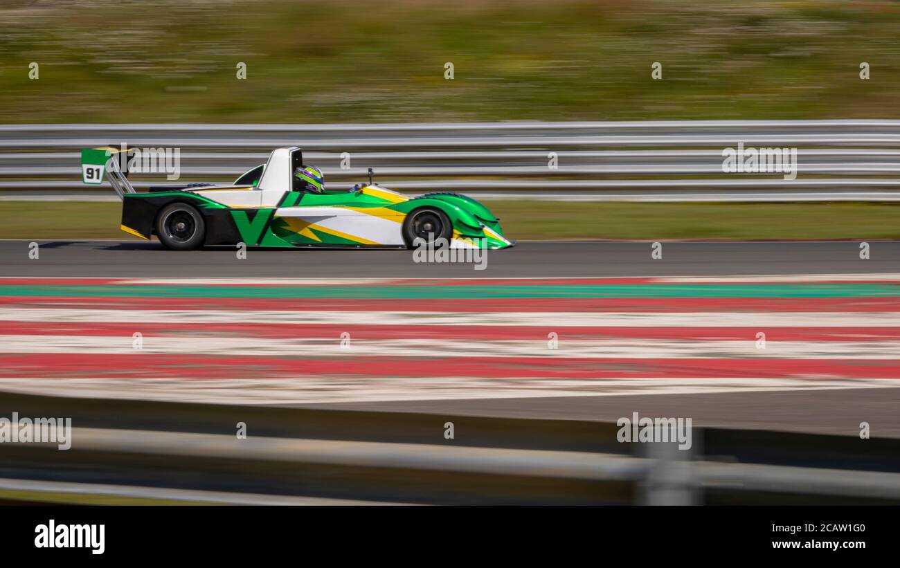 A panning shot of a white and green racing car as it circuits a track ...