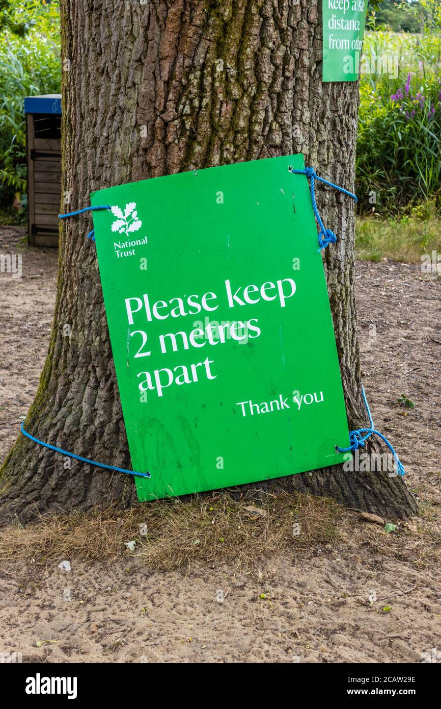 A green National Trust social distancing sign on a tree at Frensham ...