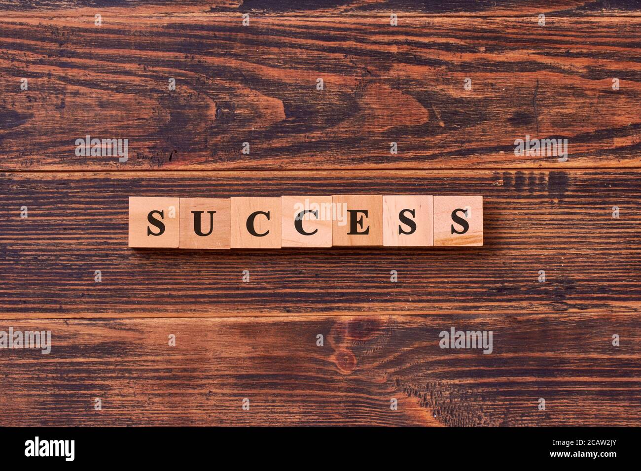 Success word lettering made of wooden cubes on dark rustic wooden ...