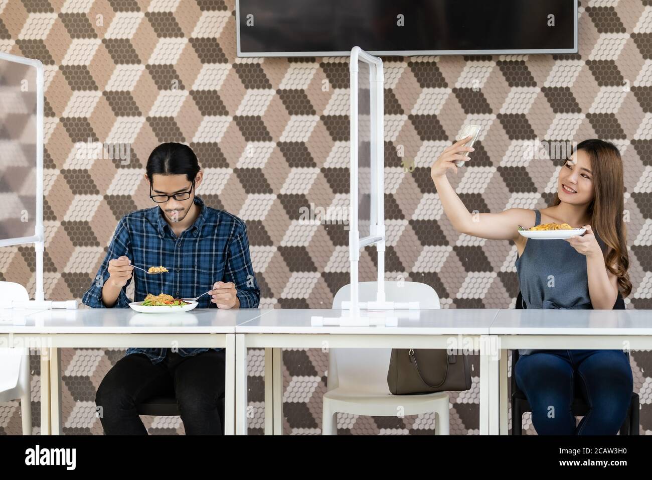 Restaurant customers have a seat with table shield partition for social ...