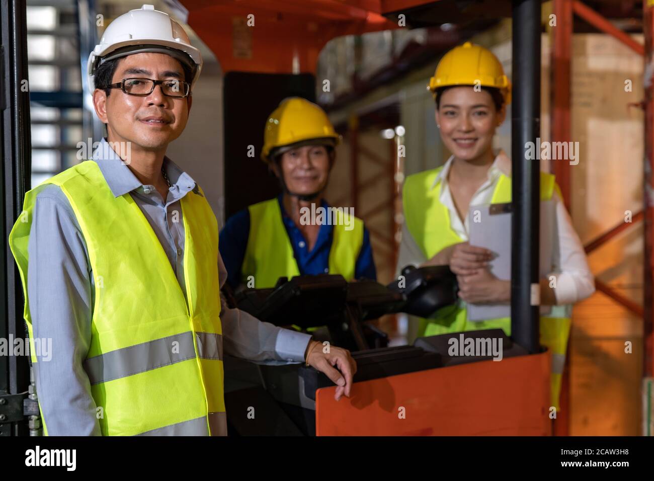 Portrait of Asian warehouse manager and his team worker with forklift ...
