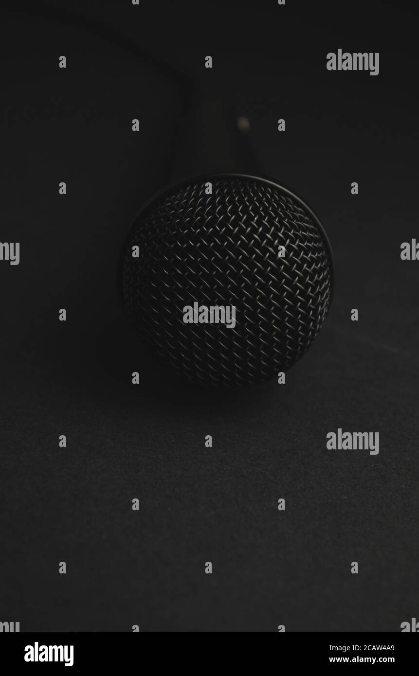 Vertical closeup shot of a black microphone on a black background Stock ...