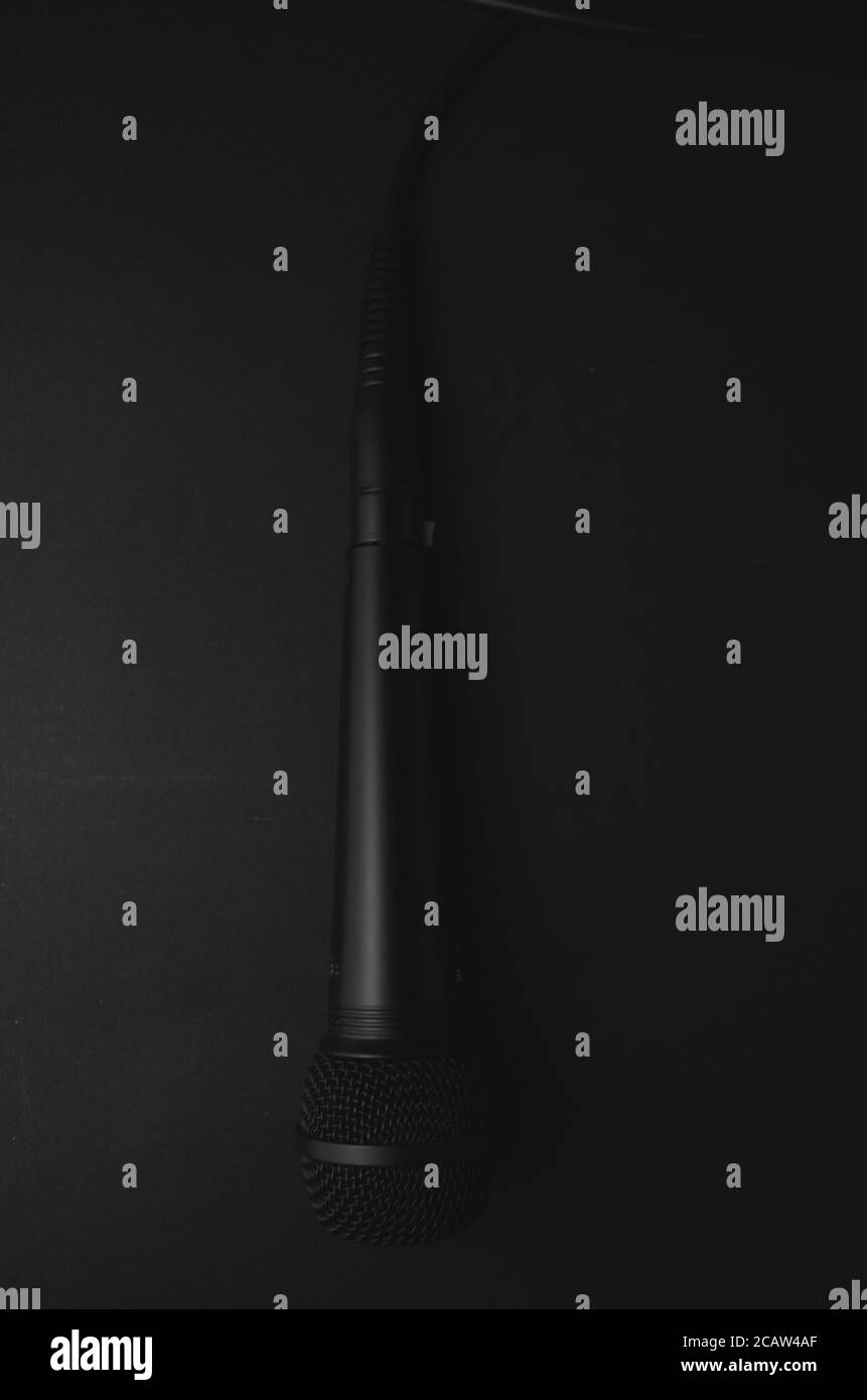 Vertical closeup shot of a black microphone on a black background Stock ...