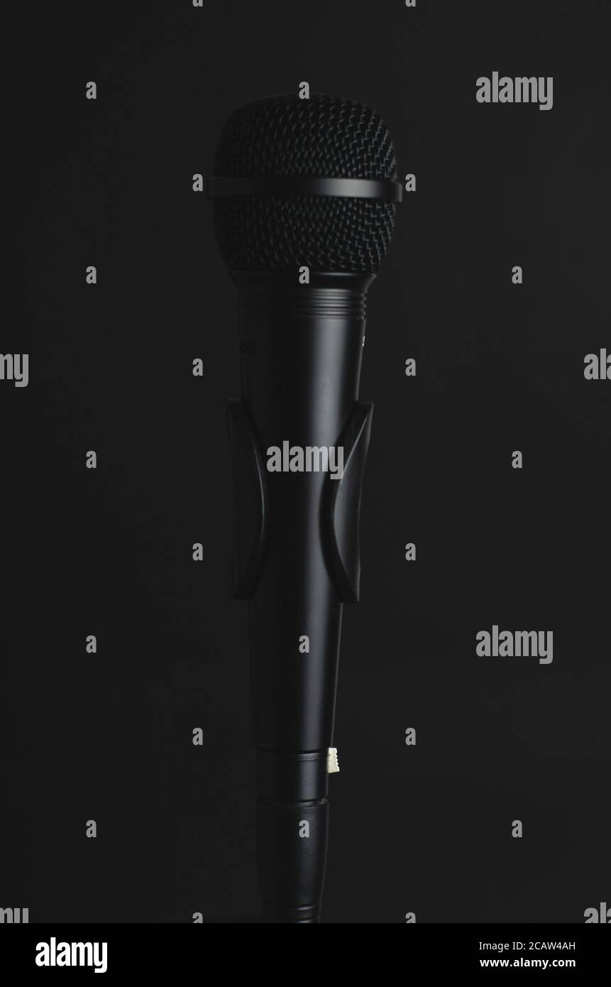 Vertical closeup shot of a black microphone on a black background Stock ...