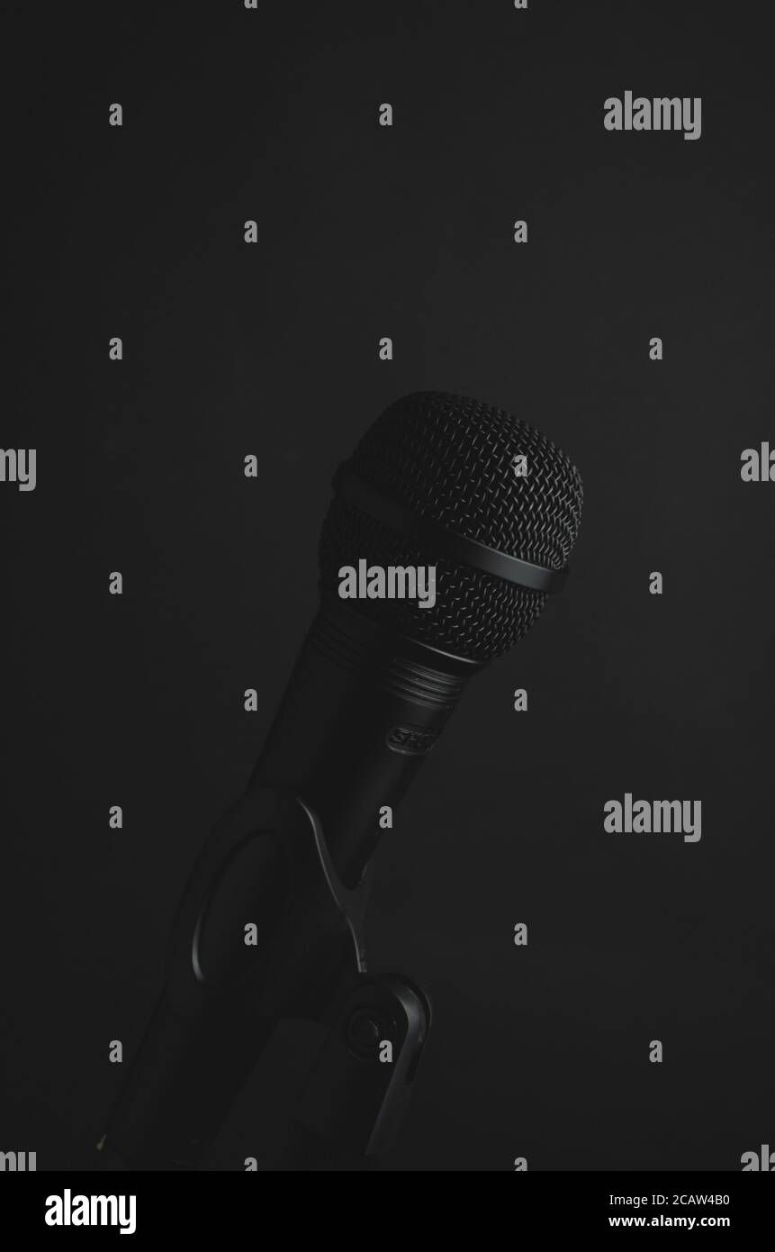 Vertical closeup shot of a black microphone on a black background Stock ...