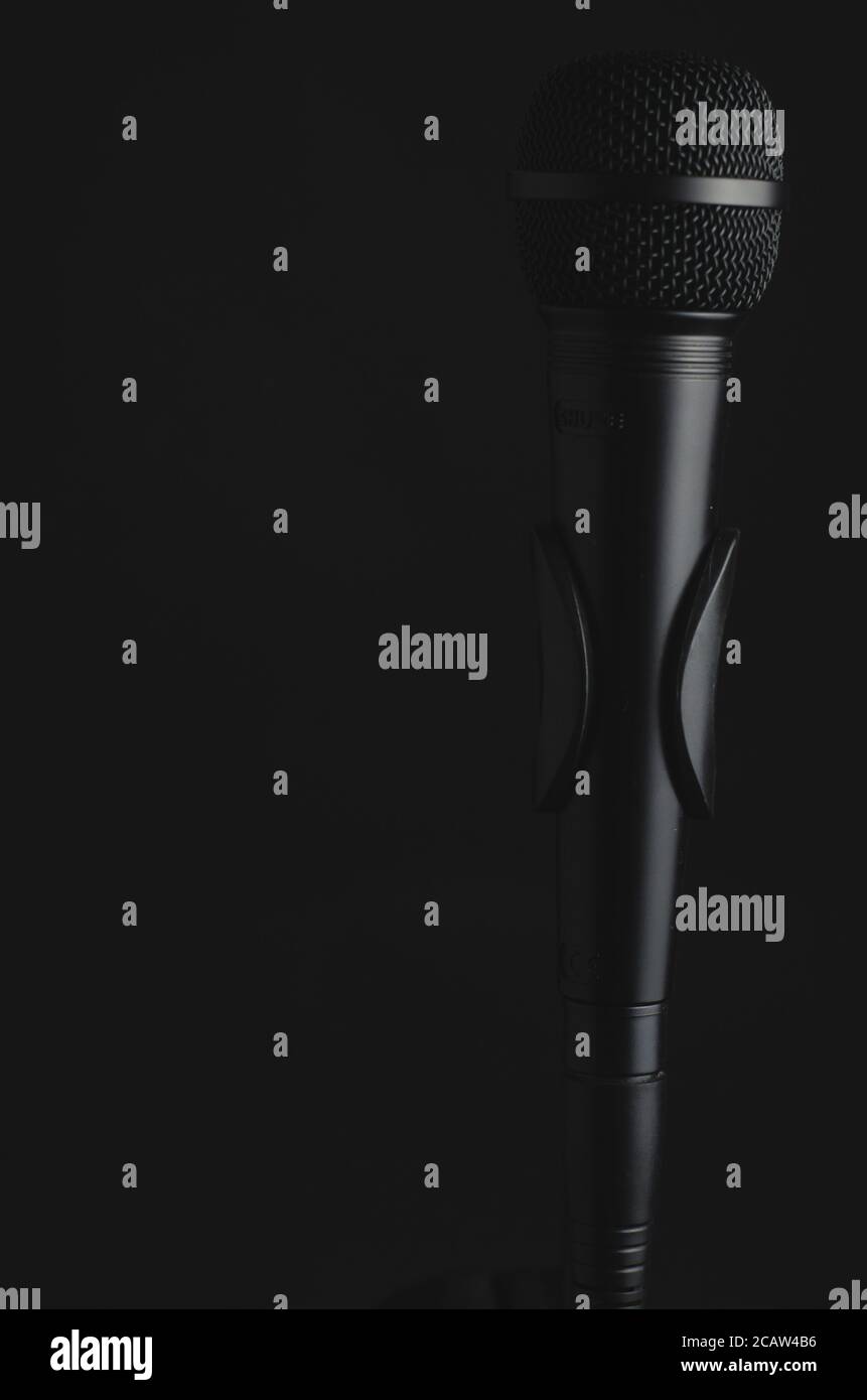 Vertical closeup shot of a black microphone on a black background Stock ...
