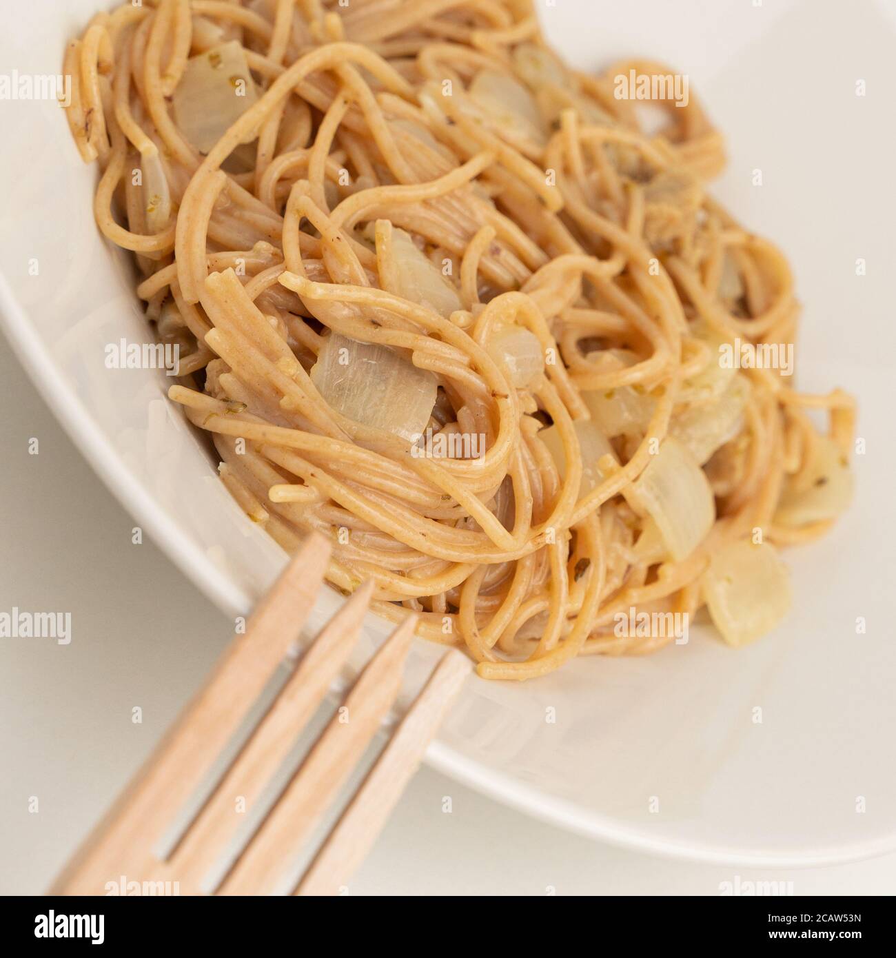 Dutch angle shot of delicious pasta with onions on a white background ...