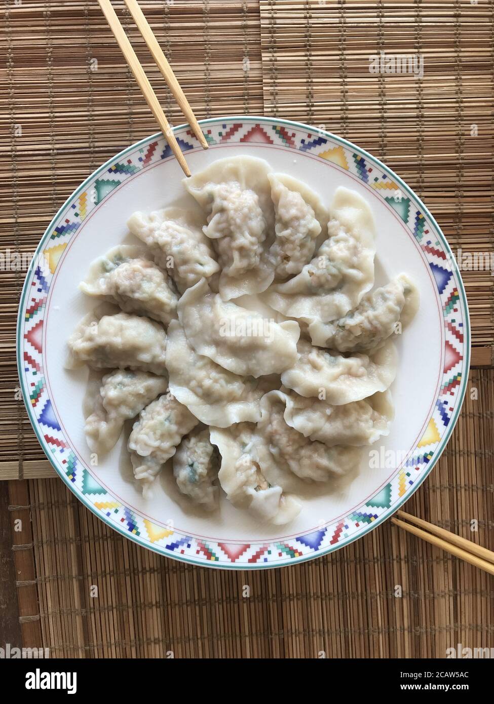 High angle closeup shot of Chinese dumplings in a white plate with ...