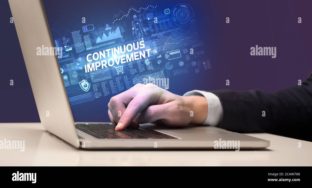 Businessman working on laptop with CONTINUOUS IMPROVEMENT inscription ...