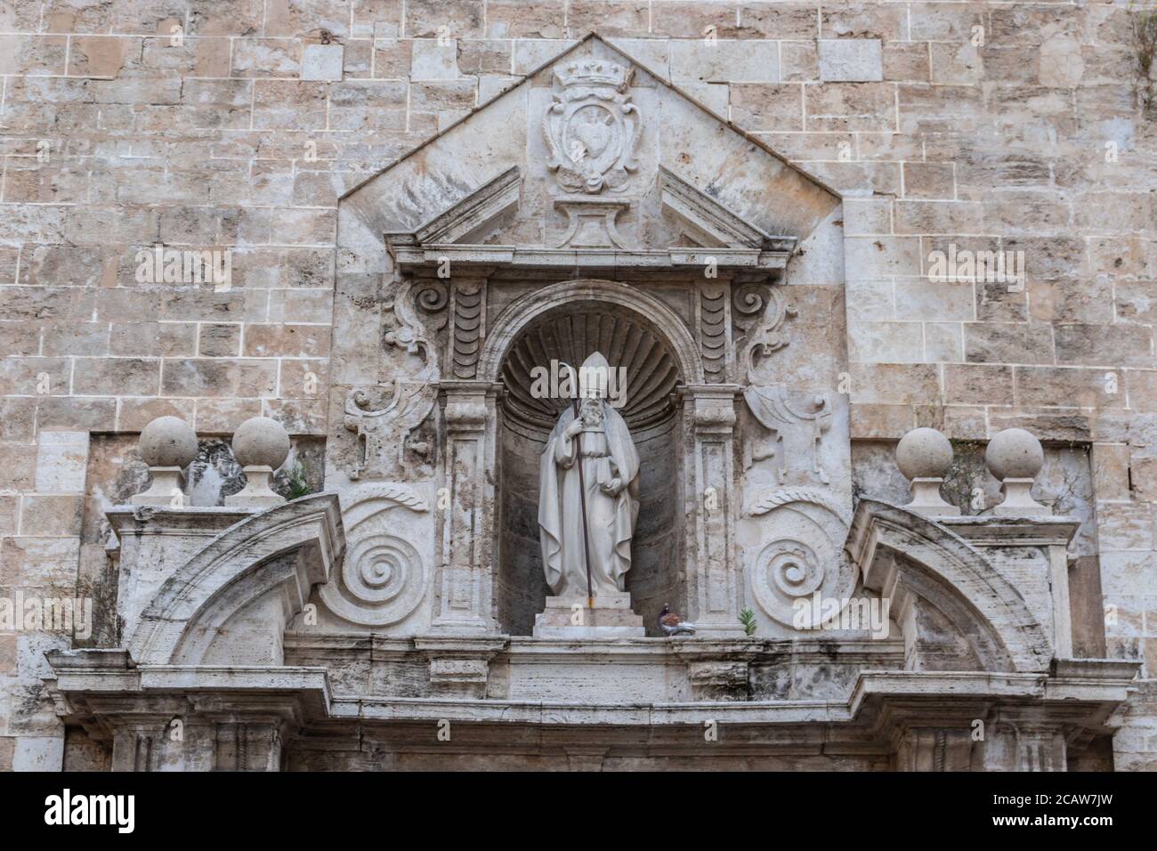Gothic bas relief on the church with a statue of priest and columns in ...