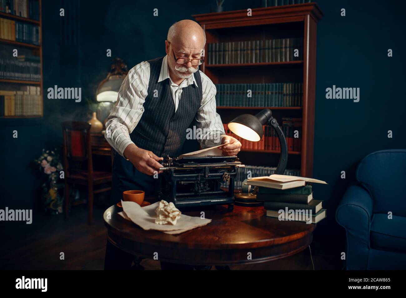 Elderly writer inserts paper into the typewriter Stock Photo - Alamy