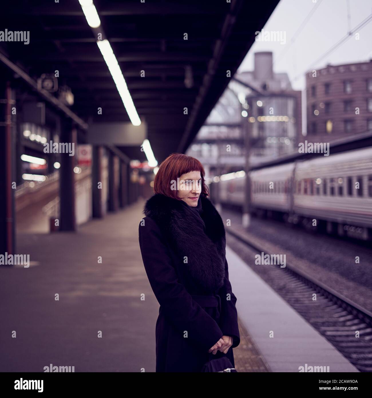 Railway station. Beautiful girl is standing on platform and waiting for ...