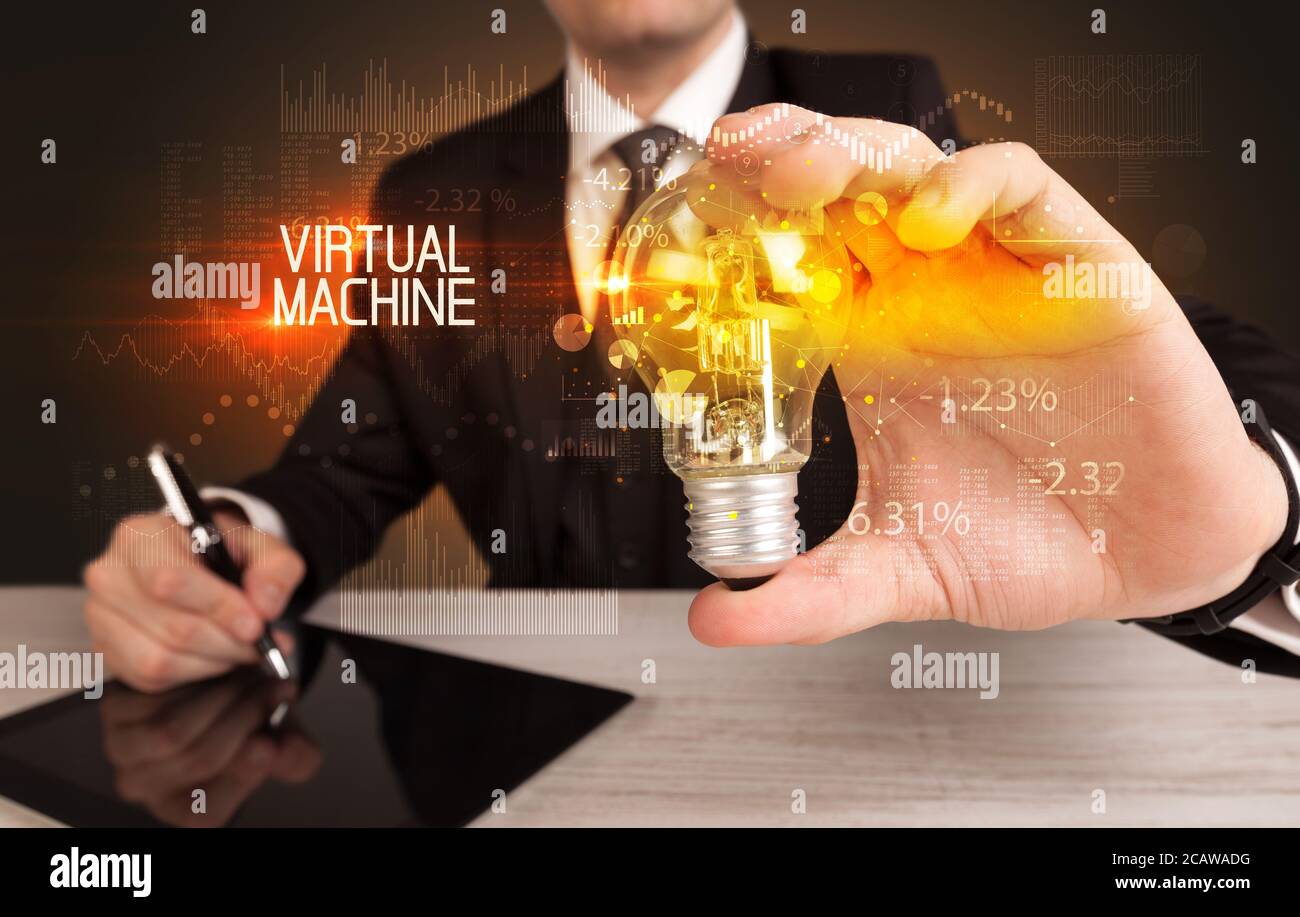 Businessman holding lightbulb with VIRTUAL MACHINE inscription ...