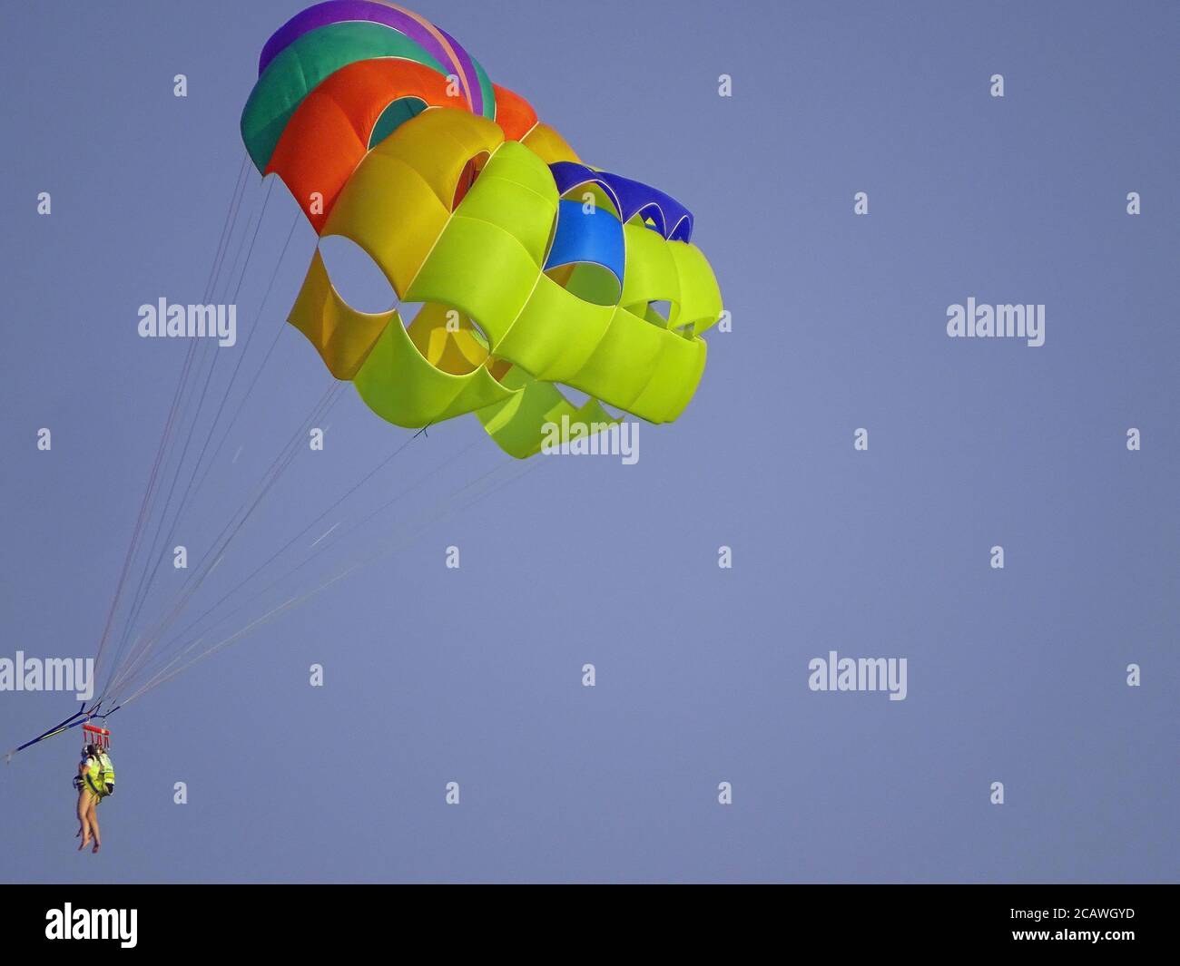 Mesmerizing shot of a couple flying with a parachute high in the sky ...