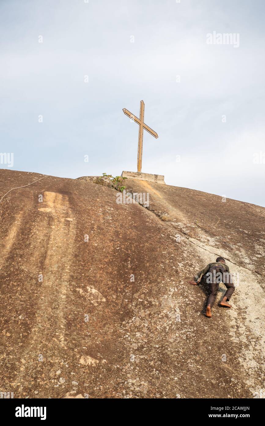 A pilgrim climbing to reach a cross on top of a rock at Katoosa Martyrs ...