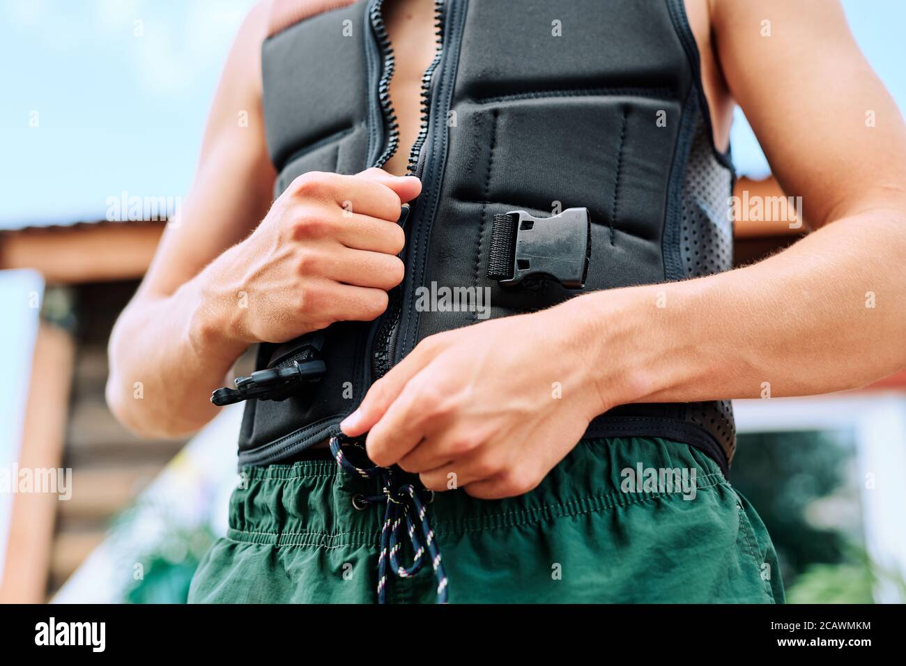 Arms of young active sportsman putting on black safety jacket and ...