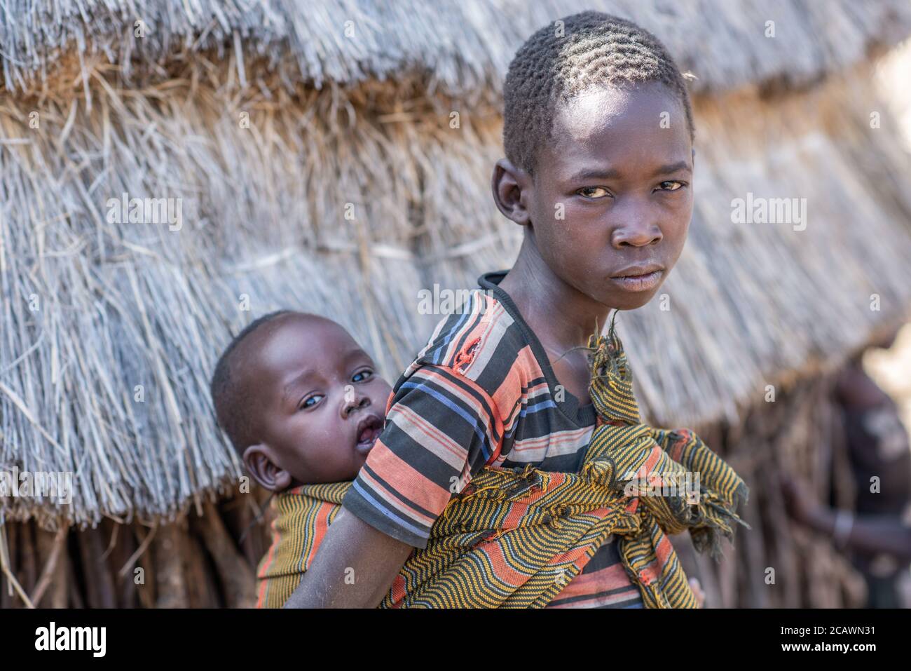Young boy carrying a baby on his back in a Karamojong village, Moroto ...