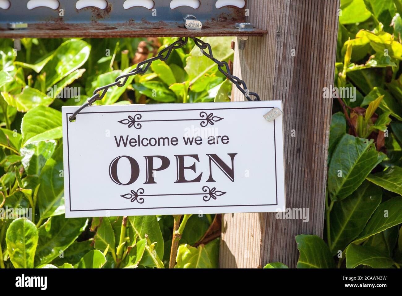 We are open sign hanging on wooded post Stock Photo - Alamy