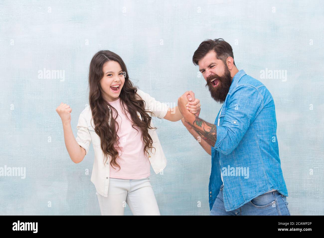 Shes champion. Happy child overcome father in arm wrestling. Girl child ...