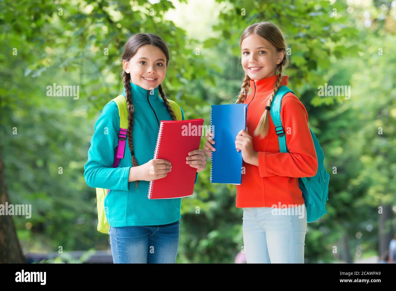 Schoolgirls with backpacks and textbooks in forest, exploring nature ...