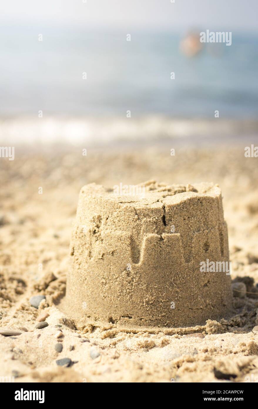 Vertical shot of a small sandcastle at beach under the sunlight with a ...