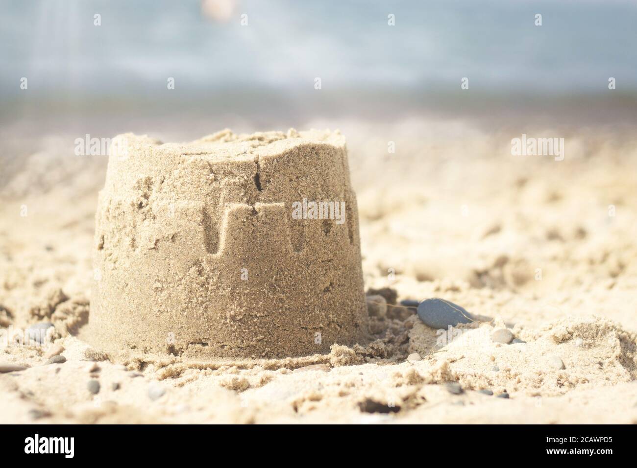 Closeup of a small sandcastle at the beach under the sunlight with a ...