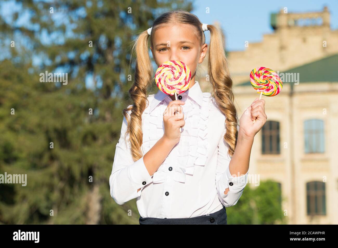Happy student girl eat colorful lollipop outdoors, yummy dessert ...