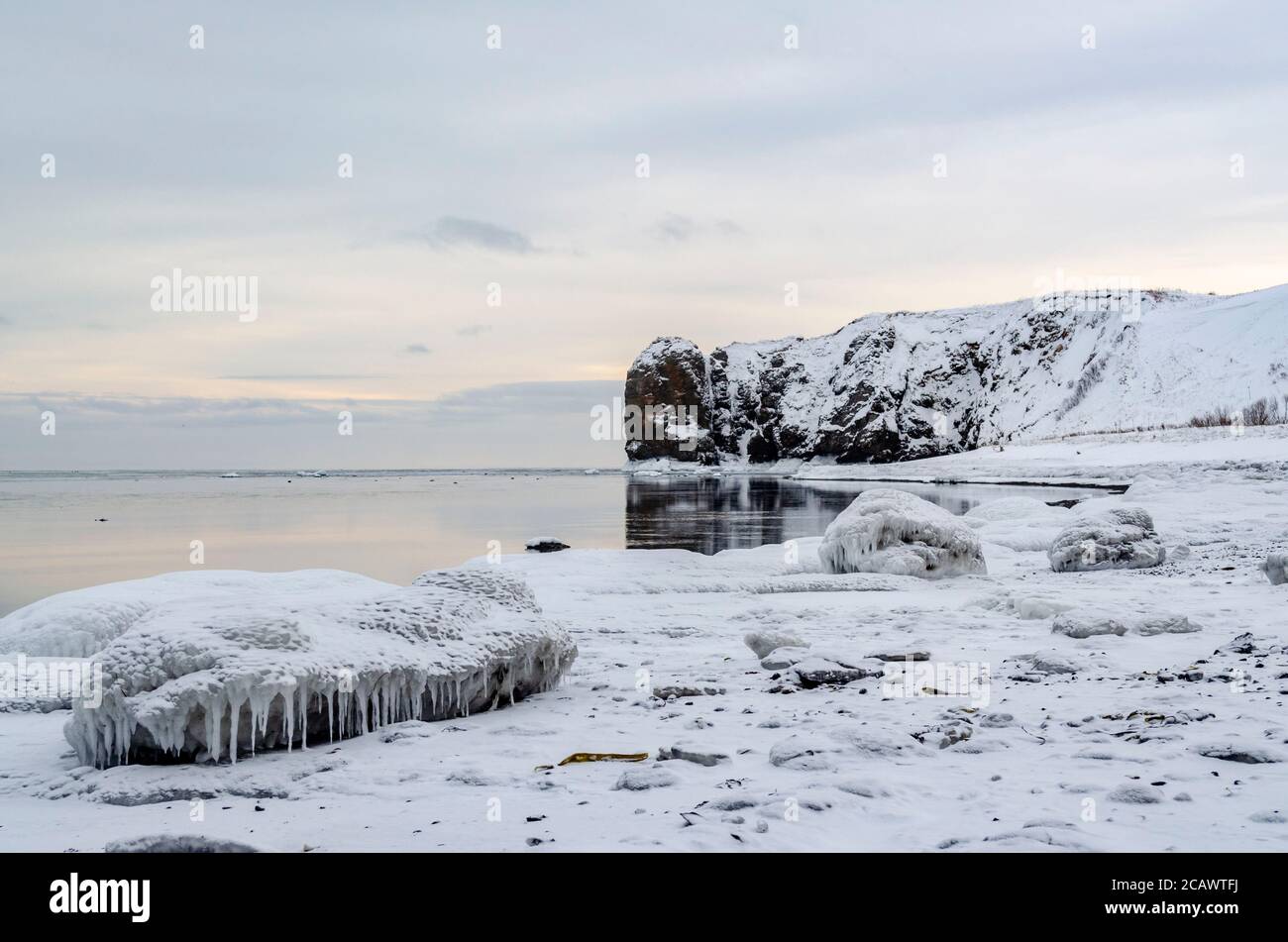 Winter beach, icicles, sea, rocks in the background, Tikhaya Bay ...