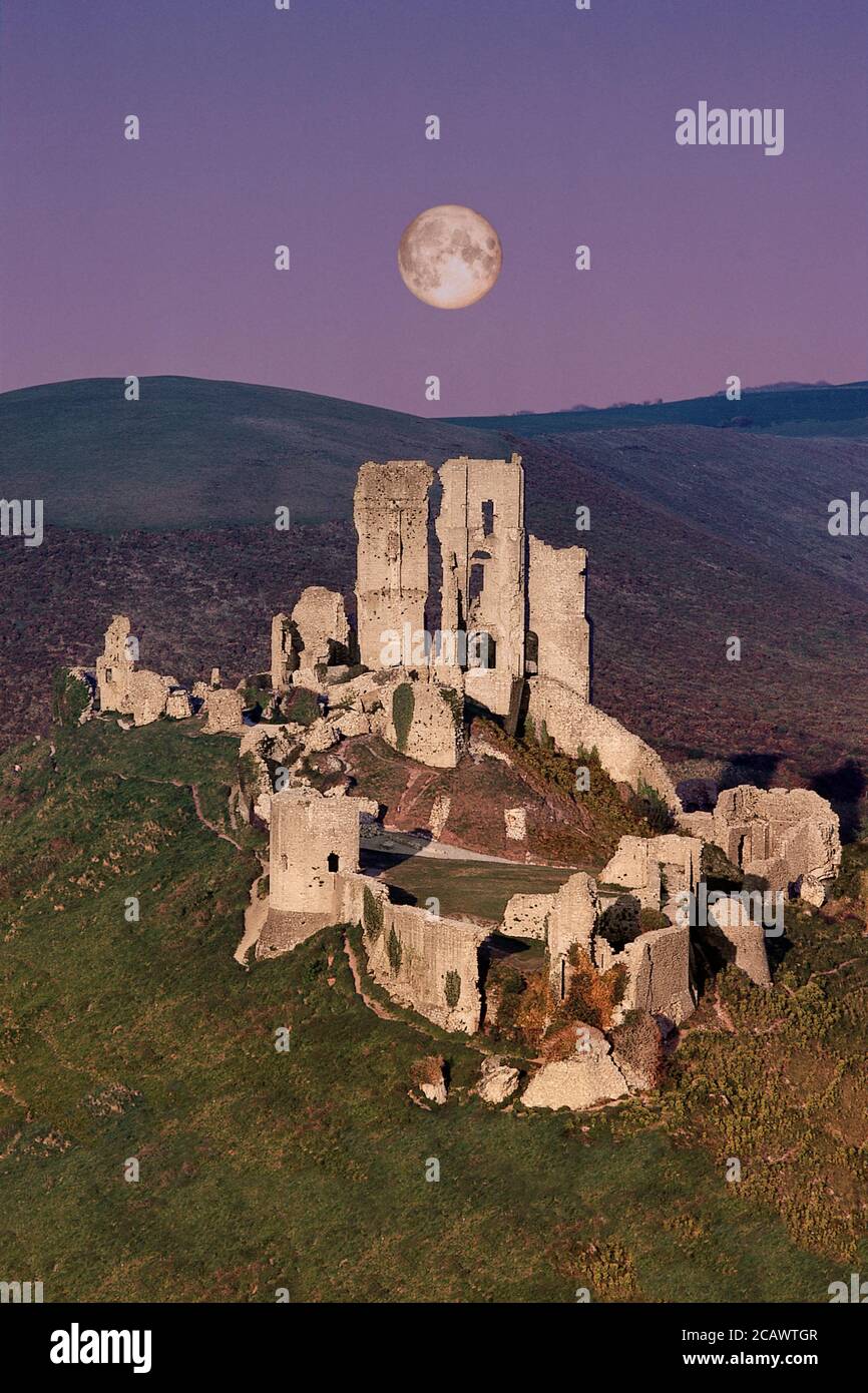 Full moon at sunset on ruined Corfe castle built in 1086 by William the ...
