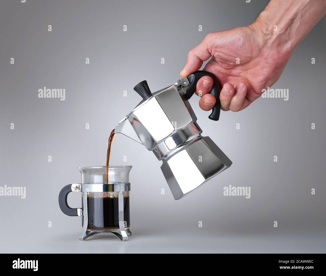Man's hand holding and pouring italian coffee into a Glass cup. There ...