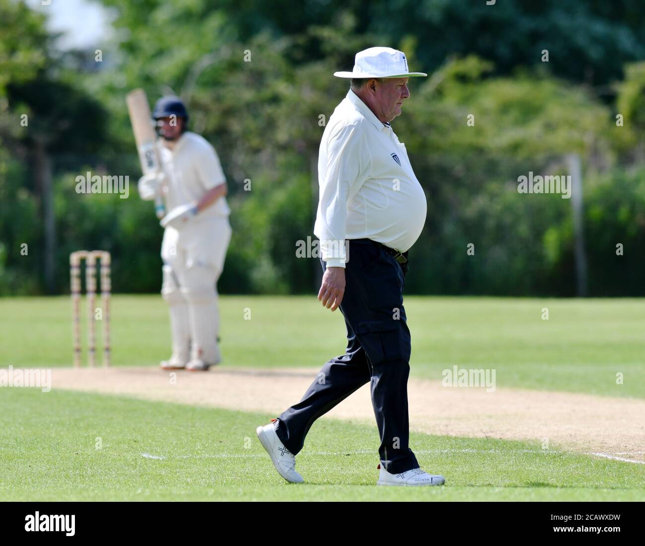 A cricket umpire walks to the wicket at the end of an over in the ...