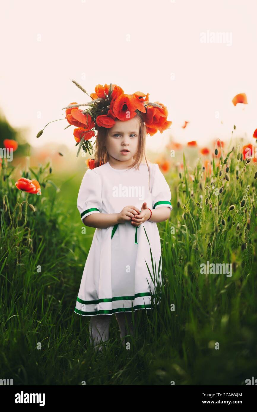 beautiful little girl with a wreath of poppies on head. cute child in ...