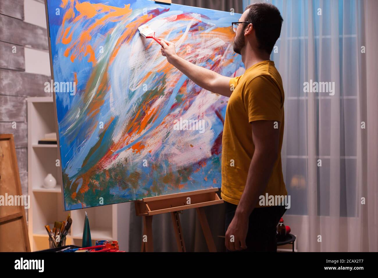 Man using oil paint on large canvas in art studio. Modern artwork paint ...