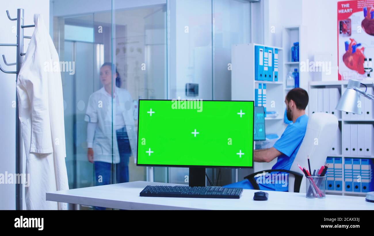 Doctor arriving in health clinic with computer having chroma key on ...